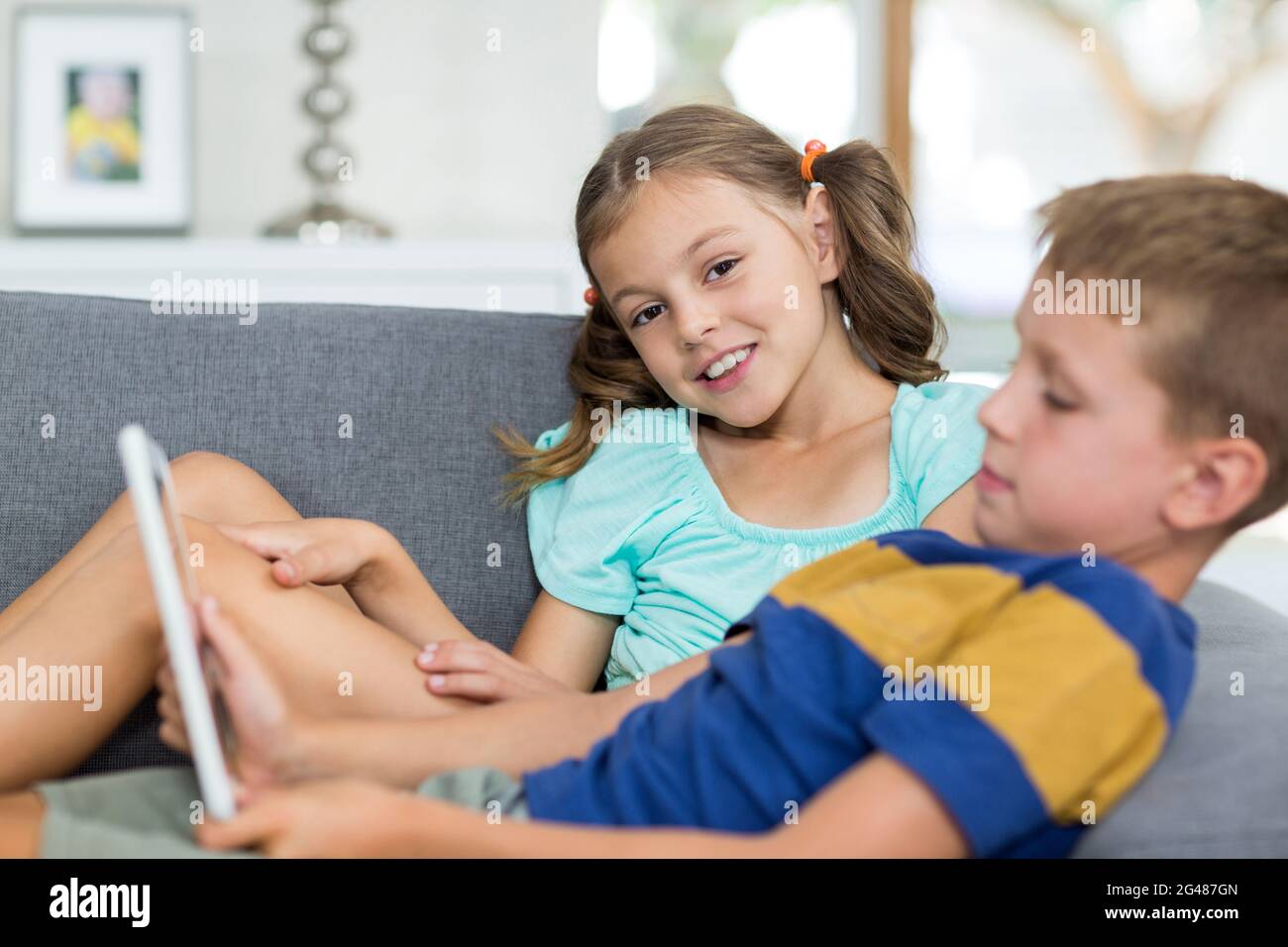 Girl smiling at camera while boy using digital tablet Stock Photo - Alamy