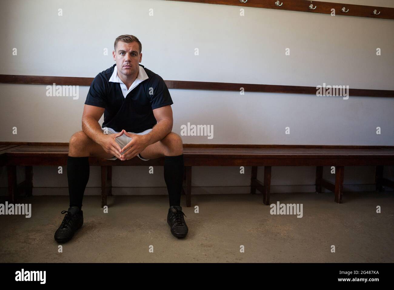 Portrait of confident rugby player sitting on bench Stock Photo - Alamy