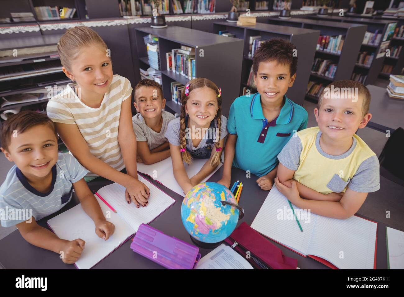 Schoolkids studying globe in library Stock Photo - Alamy