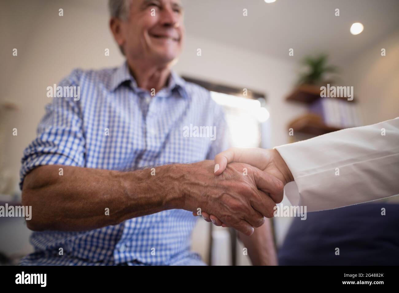 Senior male patient shaking hands with female therapist Stock Photo - Alamy