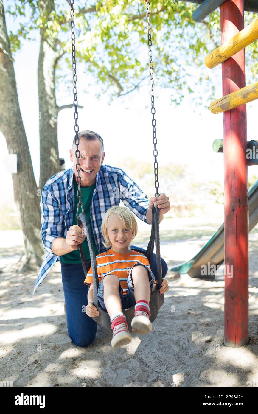 Portrait of happy father pushing son sitting on swing Stock Photo - Alamy