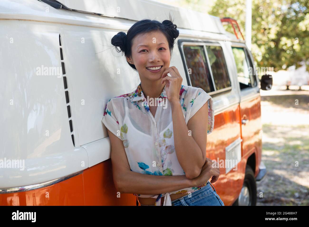 Woman leaning on camper van in the park Stock Photo - Alamy
