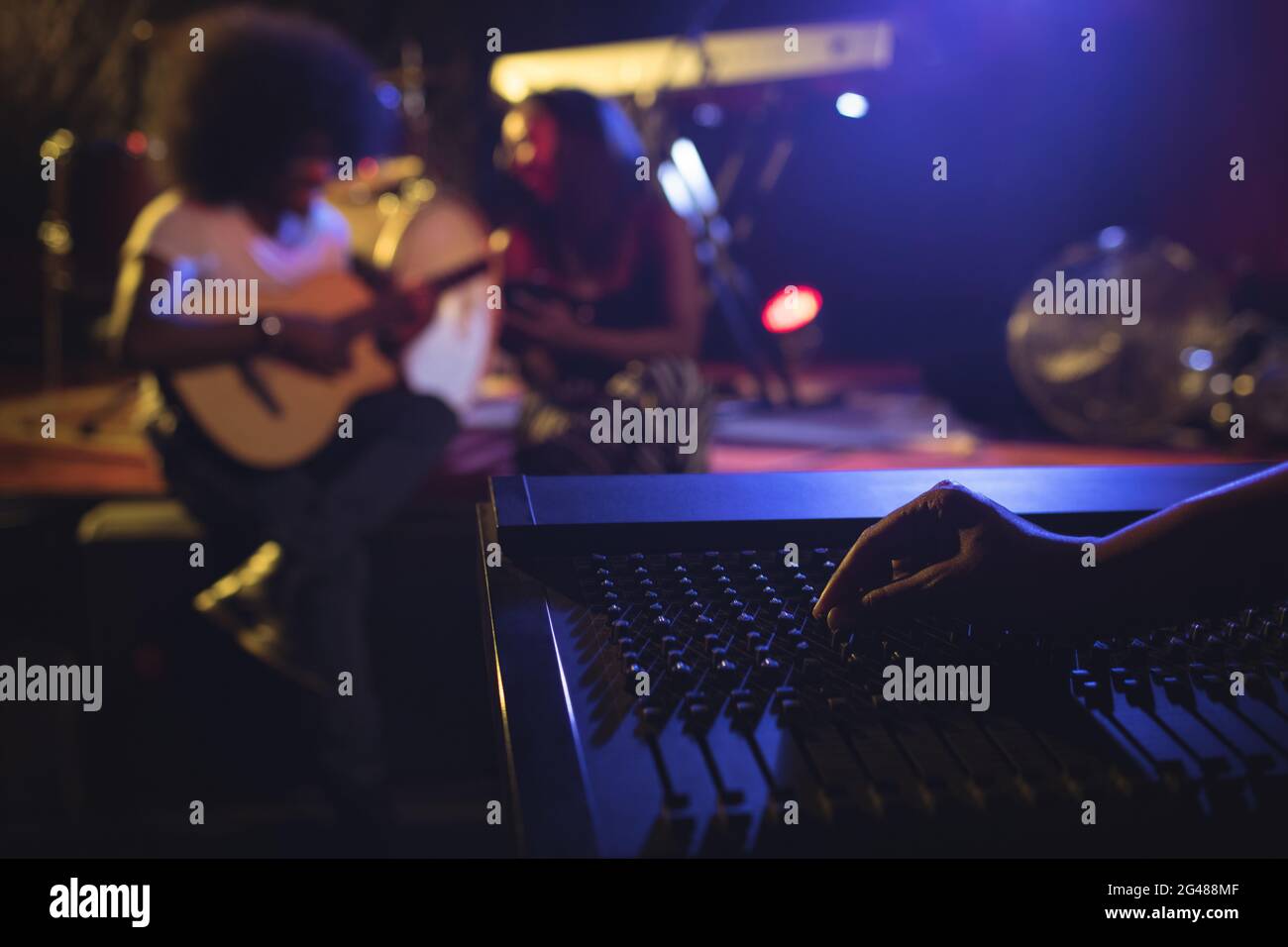 Hand operating sound mixer while musicians practicing in nightclub ...