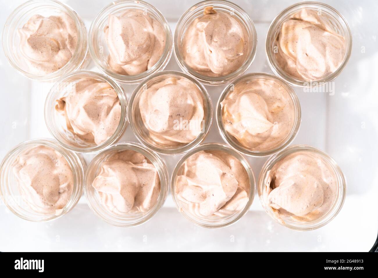 Scooping mixture into the small glass jars to make homemade chocolate ...