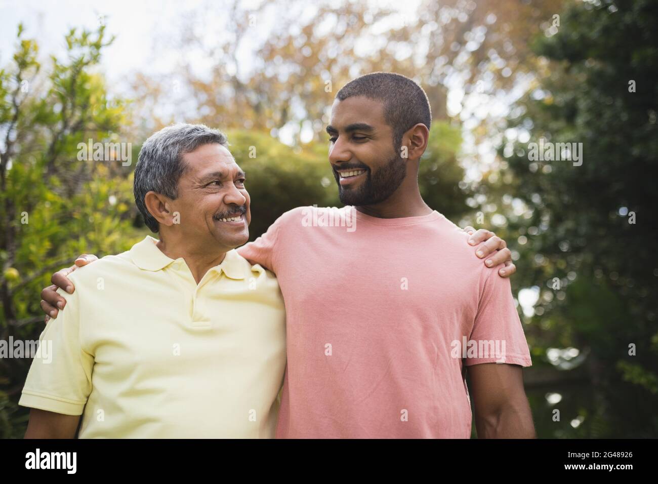 Smiling man looking at his father against trees Stock Photo - Alamy