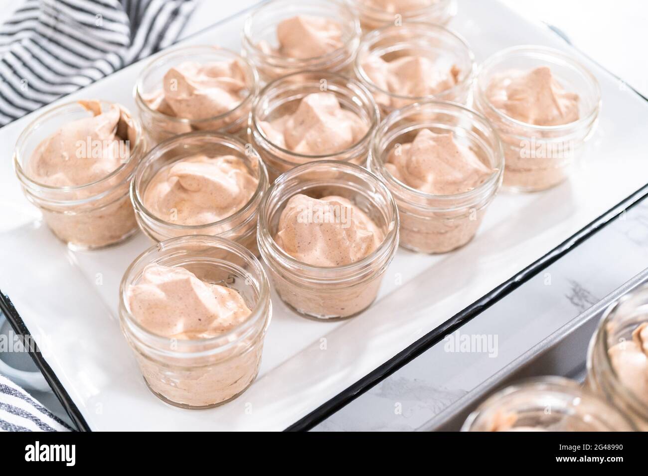 Scooping mixture into the small glass jars to make homemade chocolate ...