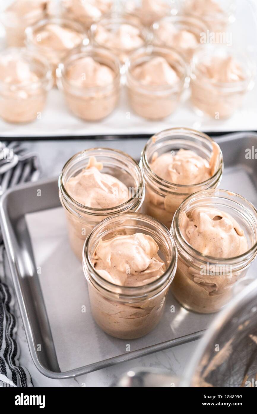 Scooping mixture into the small glass jars to make homemade chocolate ...