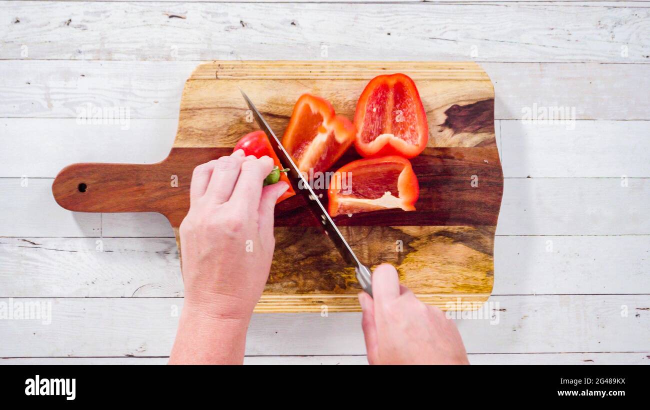 Flat lay. Mincing organic red bell peppers on a wood cutting board ...