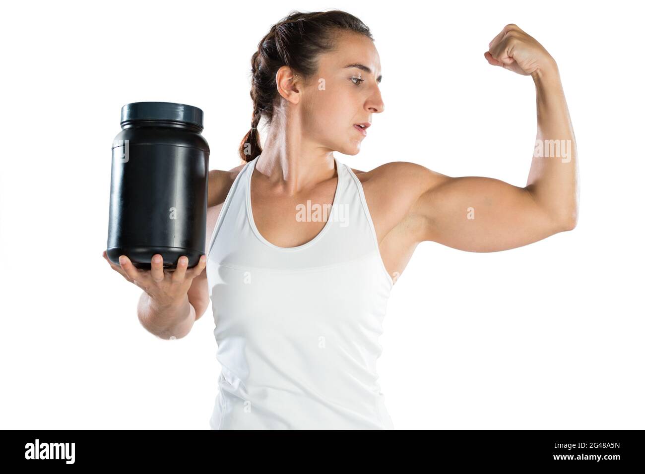 Female athlete flexing muscles while holding supplement jar Stock Photo ...