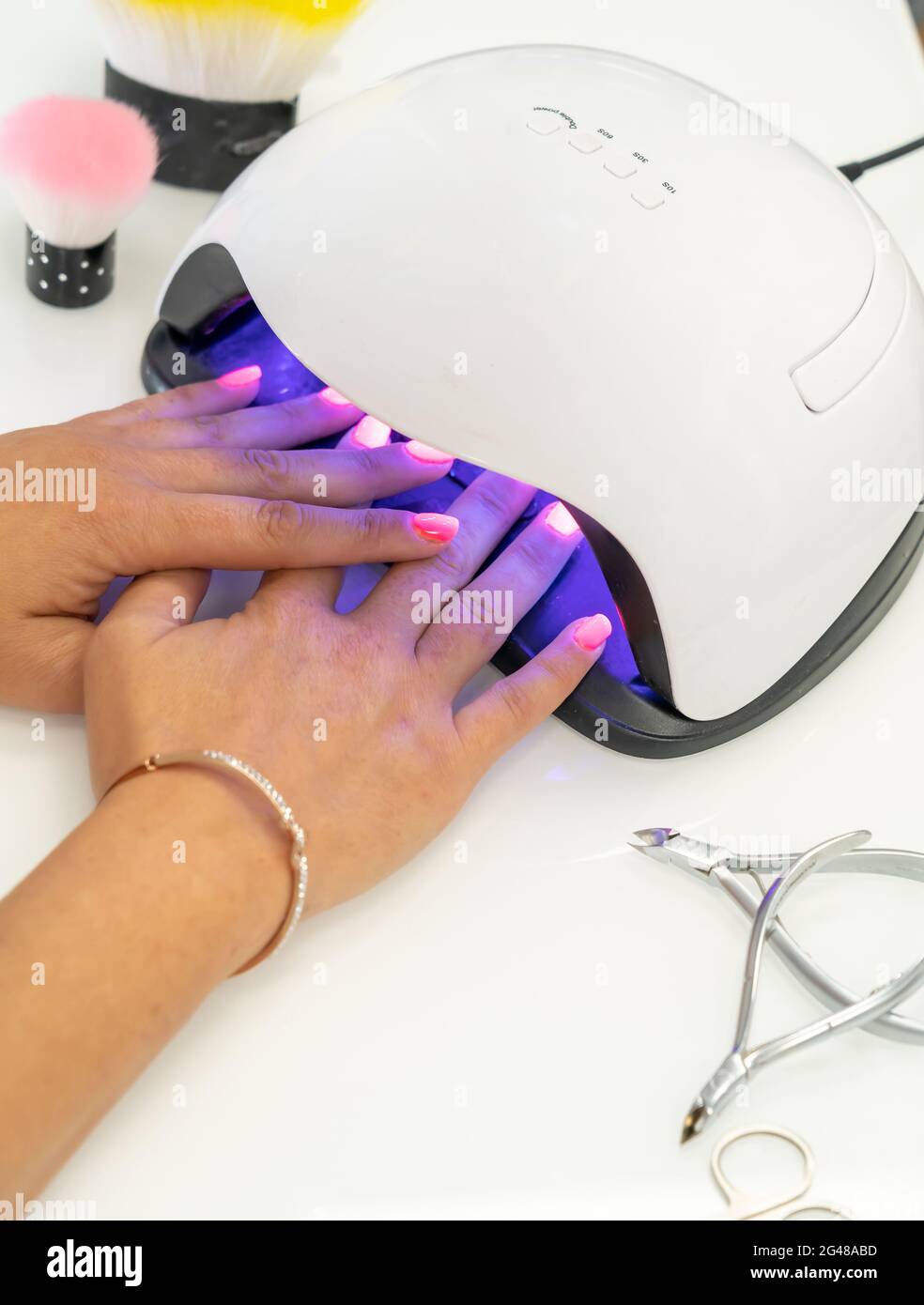 Female drying gel polish in a lamp Stock Photo - Alamy