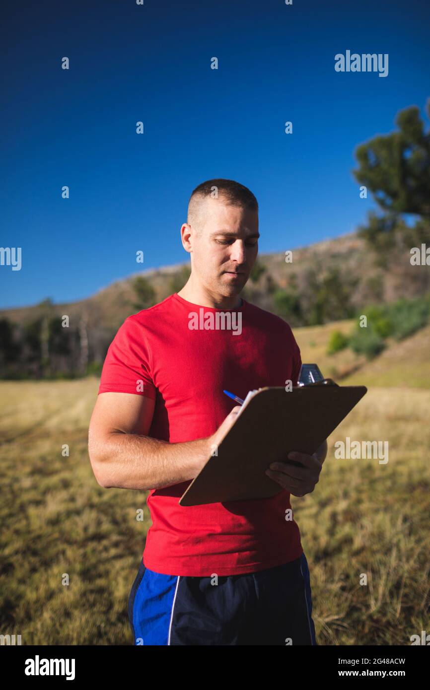 Trainer writing on clipboard in the boot camp Stock Photo - Alamy