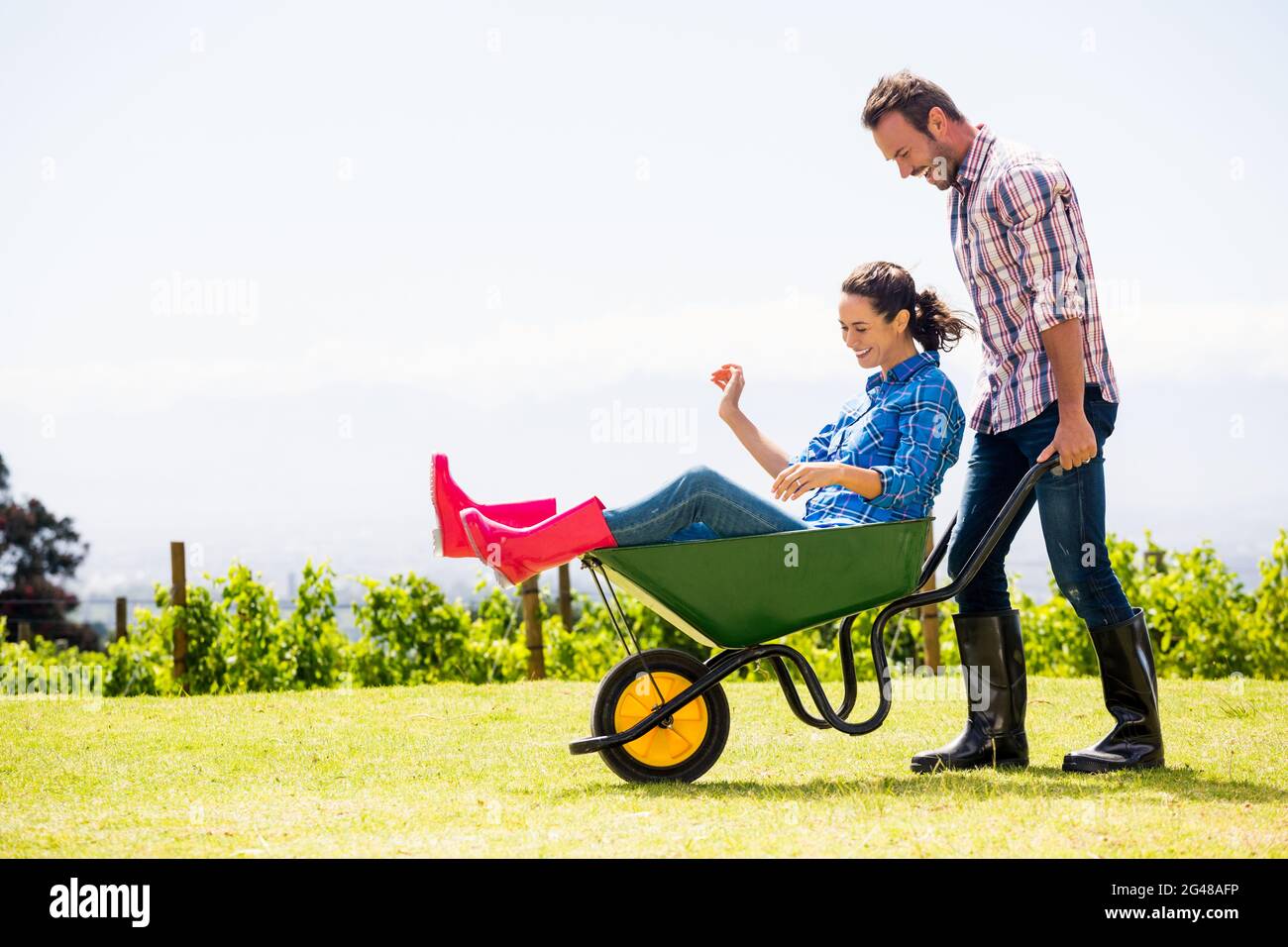 Young man pushing woman sitting in wheelbarrow Stock Photo - Alamy