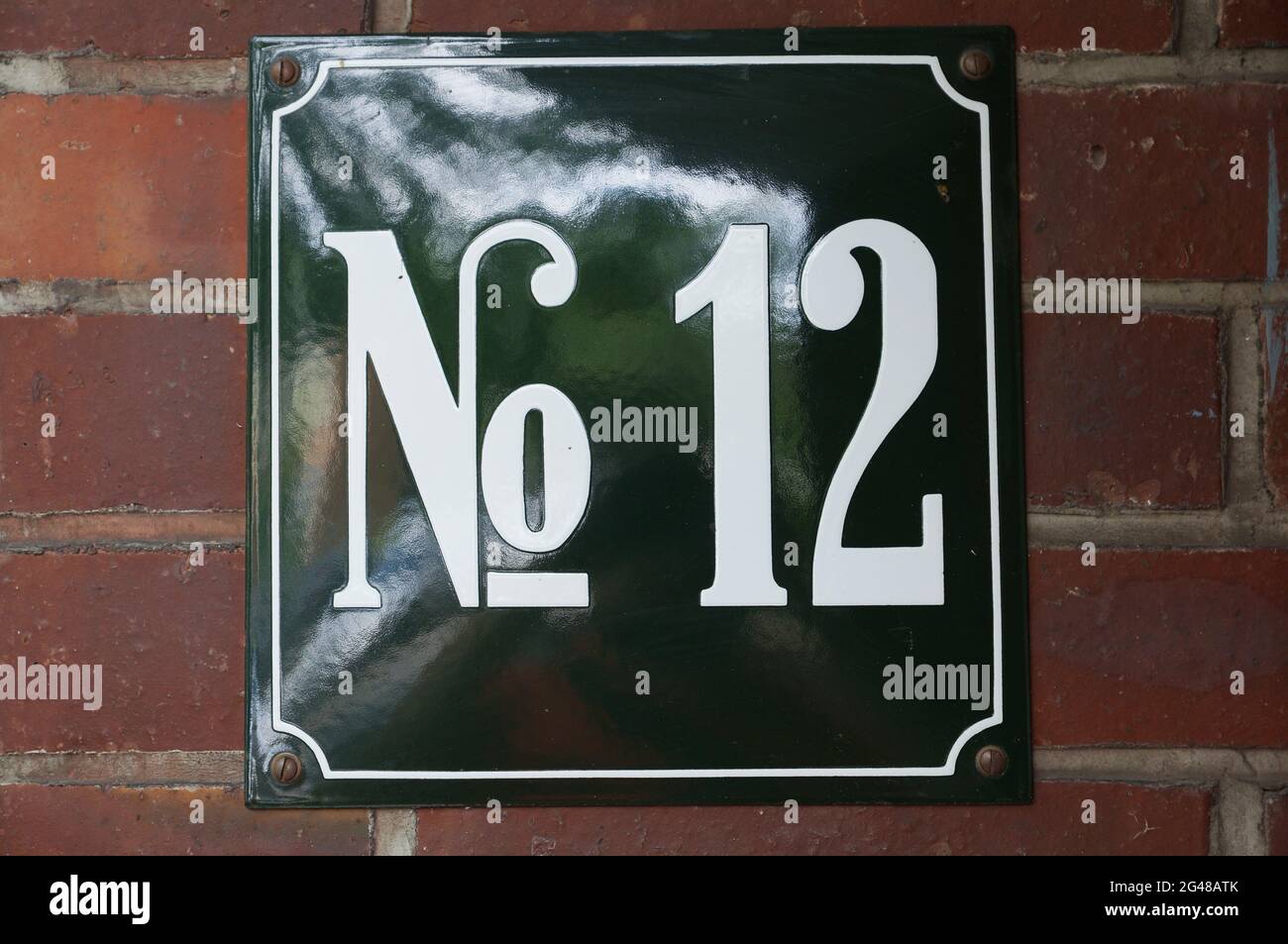 House number "12" attached to a brick wall Stock Photo - Alamy