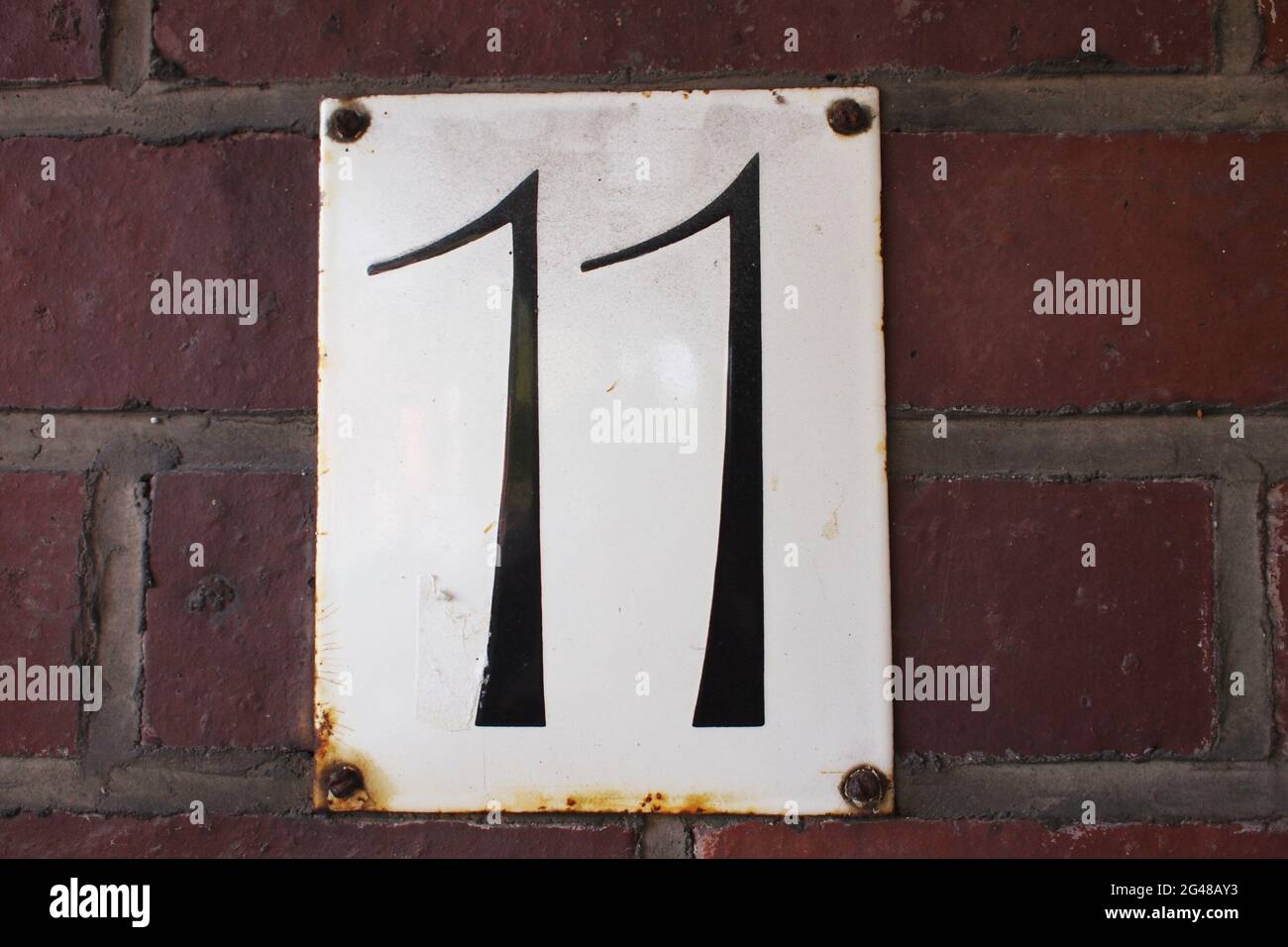 House number "11" attached to a brick wall Stock Photo - Alamy