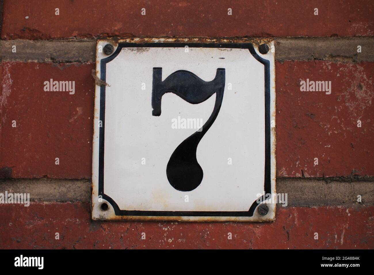 House number "7" attached to a brick wall Stock Photo - Alamy