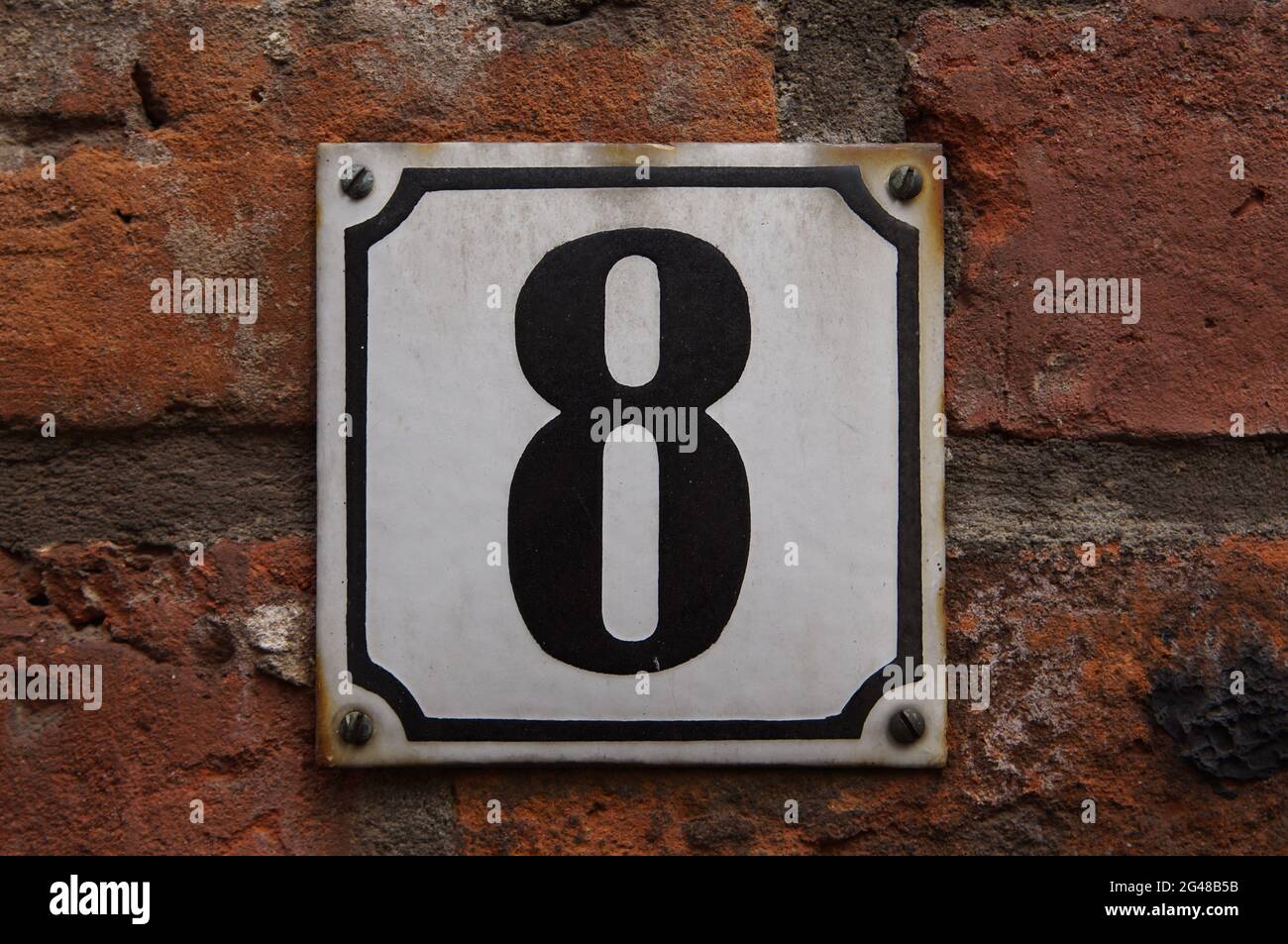 House number "8" attached to a brick wall Stock Photo - Alamy