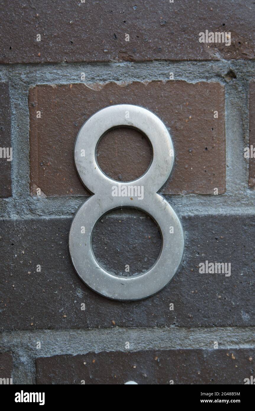 House number "8" attached to a brick wall Stock Photo - Alamy