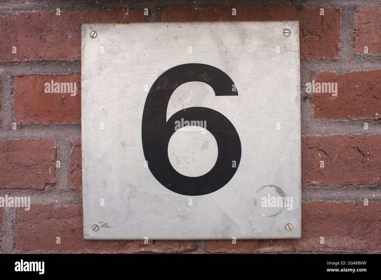 House number "6" attached to a brick wall Stock Photo - Alamy
