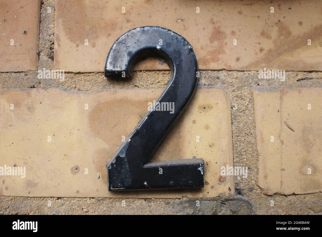 House number "2" attached to a brick wall Stock Photo - Alamy