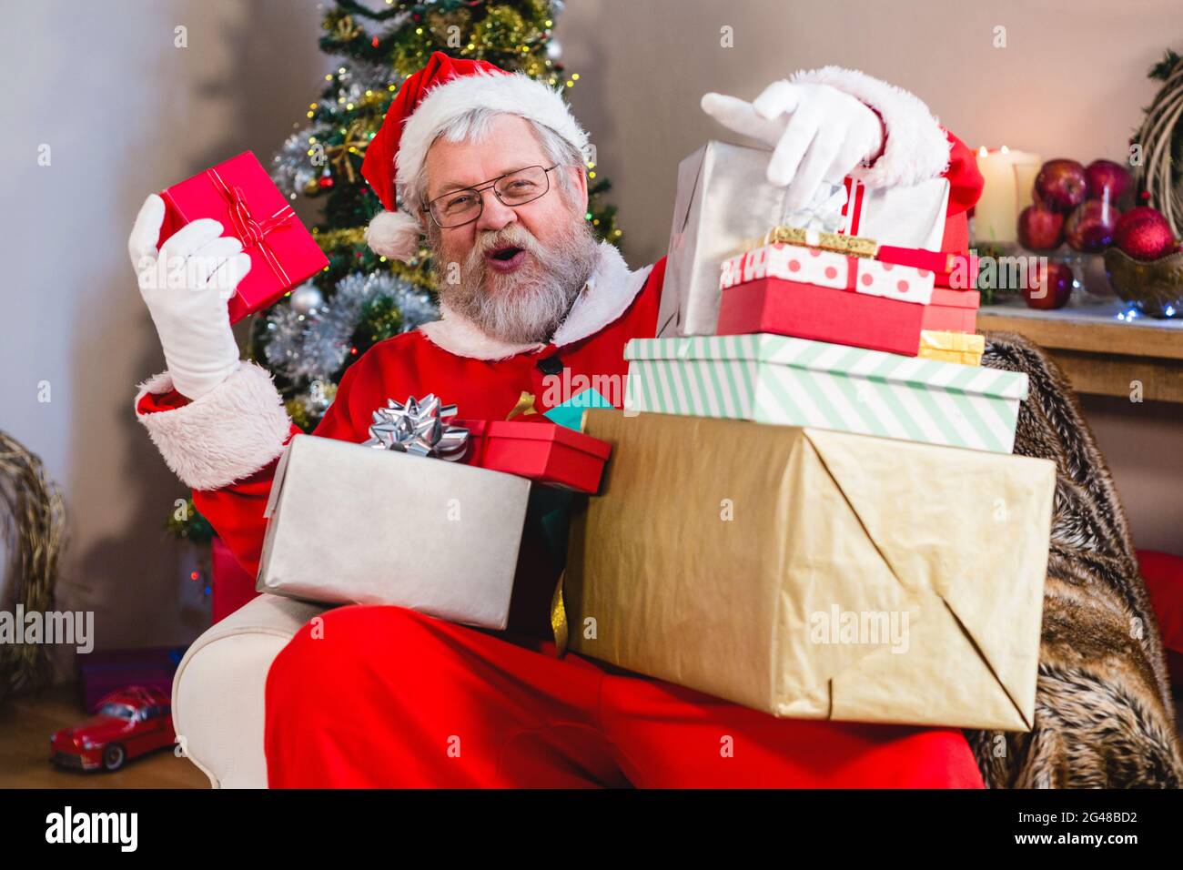 Santa sitting on the sofa with stack of gifts Stock Photo - Alamy