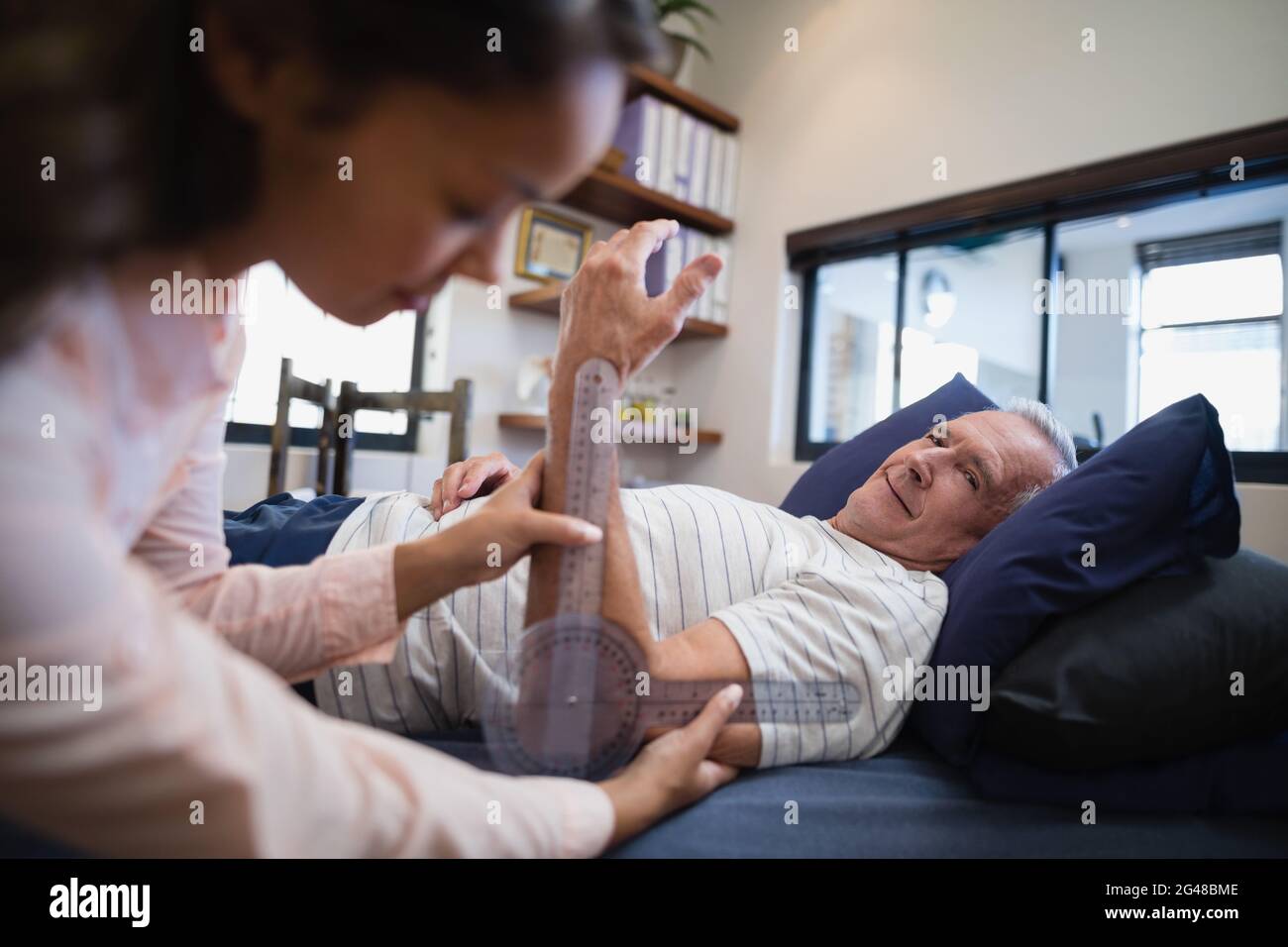 Senior male patient looking at female doctor measuring elbow Stock ...