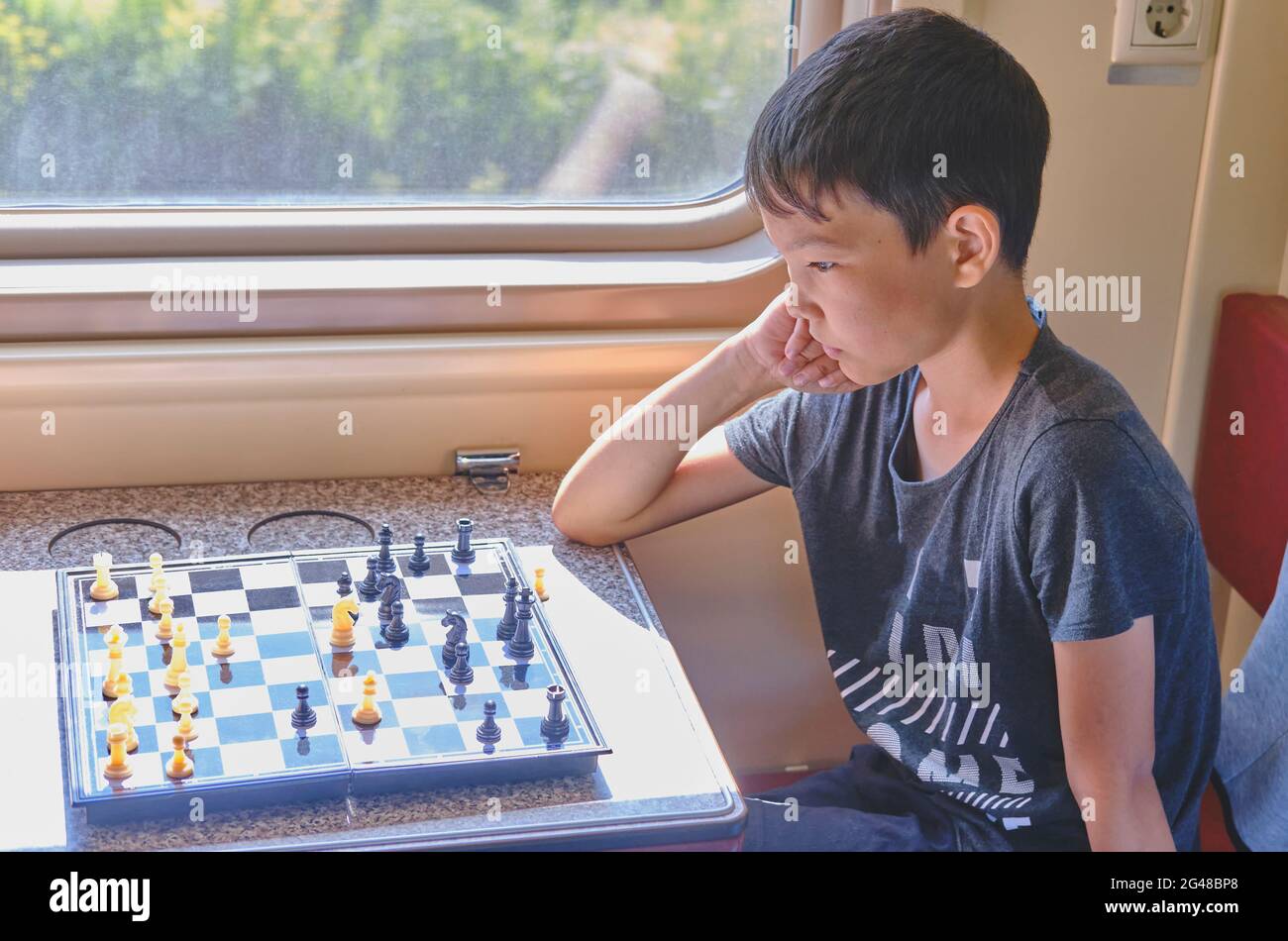 Young boy playing chess near window in the train. Indoor games concept ...