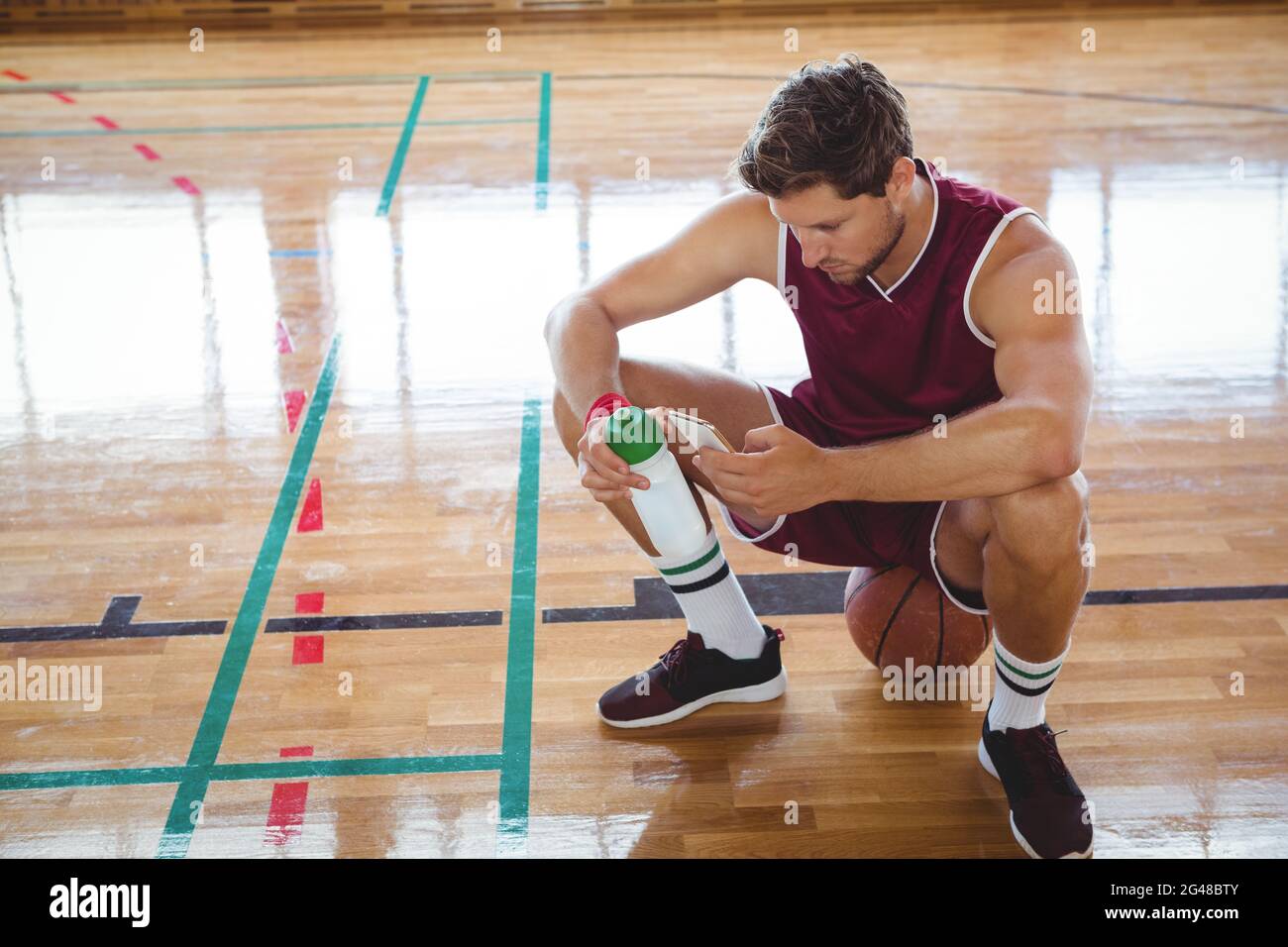 High angle view of man using mobile phone while sitting on basketball ...