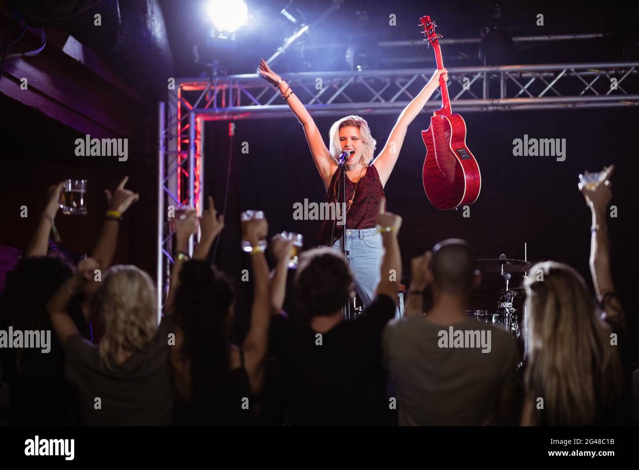 Female performer with arms raised singing during music event Stock ...