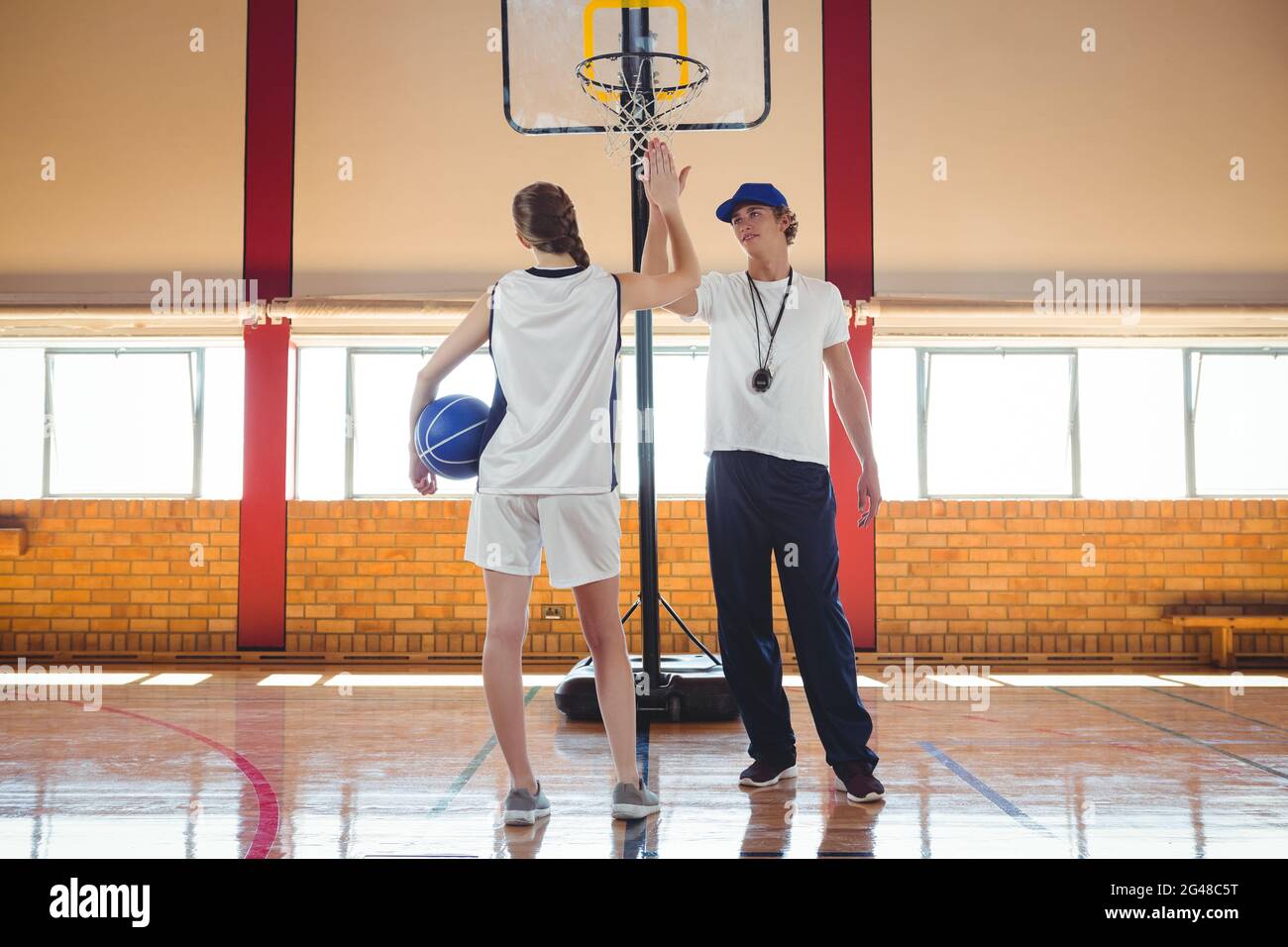Full length of basketball player high fiving with male coach Stock ...