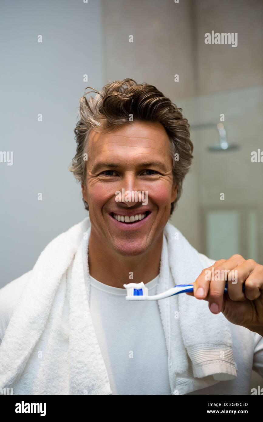 Man holding toothbrush with toothpaste in bathroom Stock Photo - Alamy