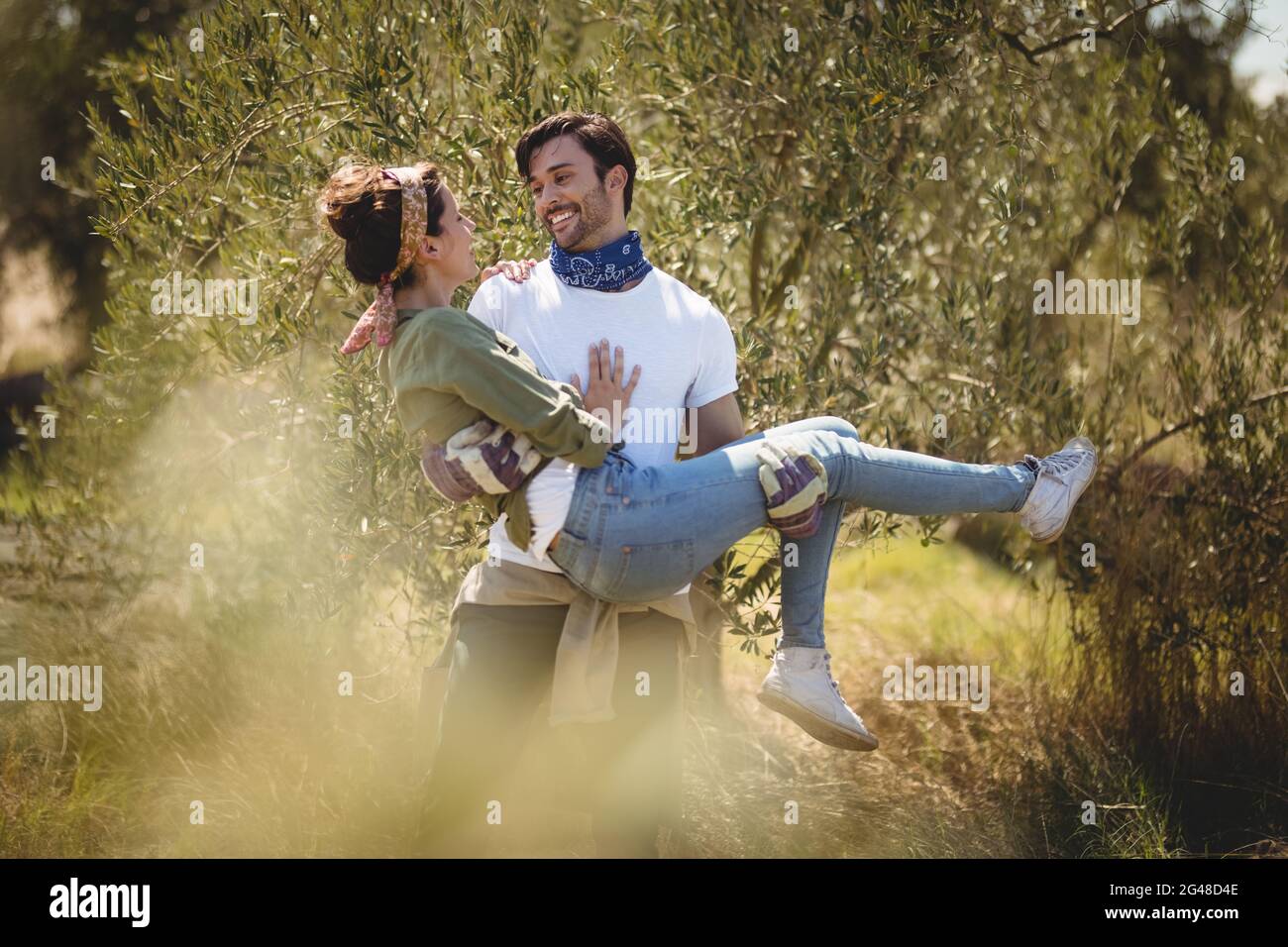 Young man carrying girlfriend by trees at farm Stock Photo - Alamy