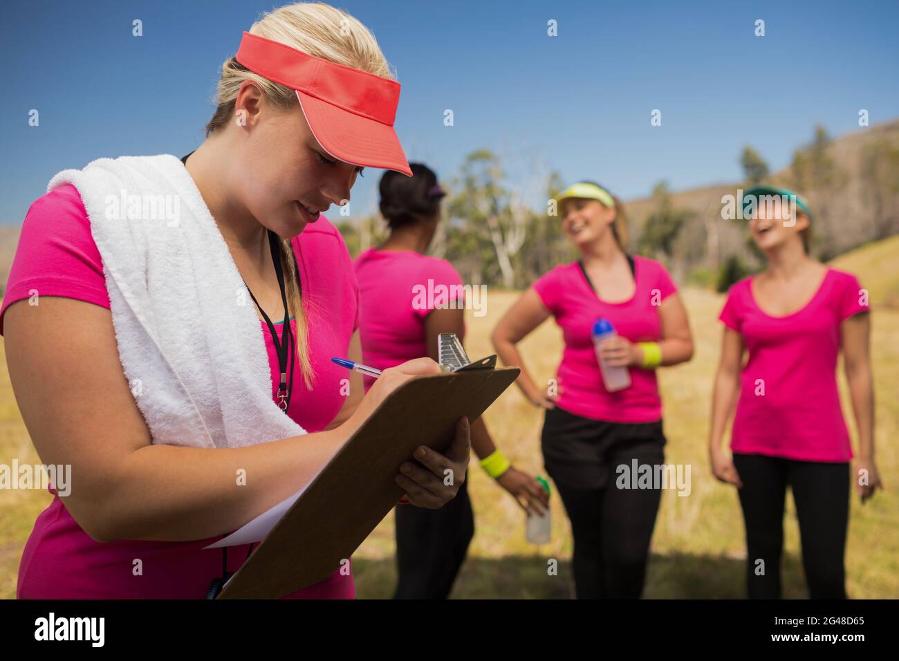 Female trainer writing on clipboard in the boot camp Stock Photo - Alamy
