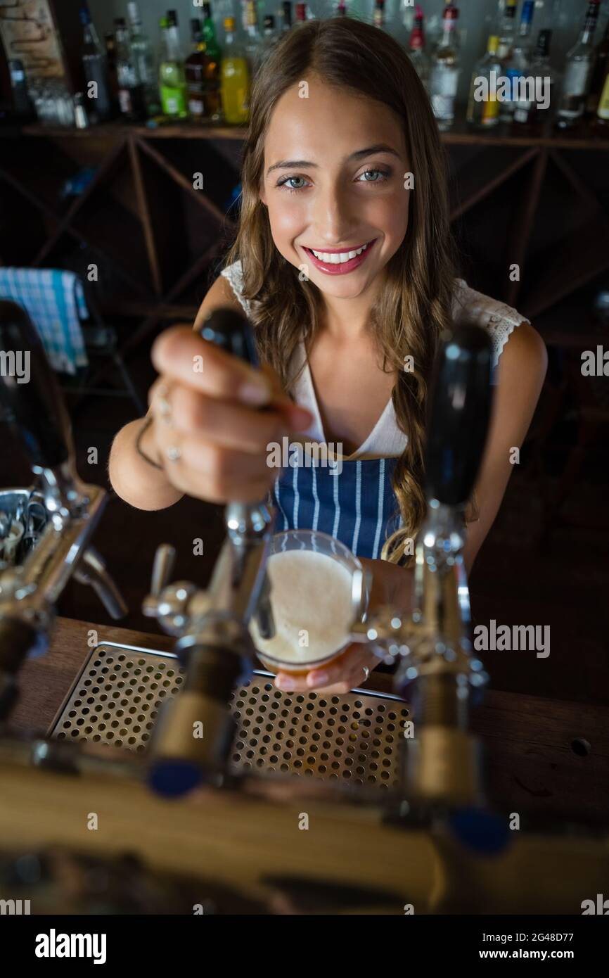 Portrait of beautiful barmaid pouring beer from tap in glass Stock ...