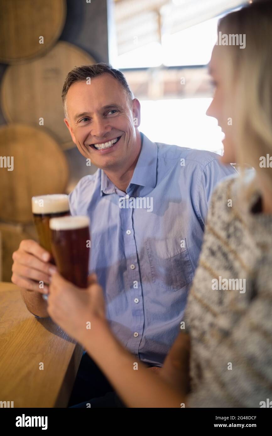 Couple interacting with each other while having beer in bar Stock Photo ...