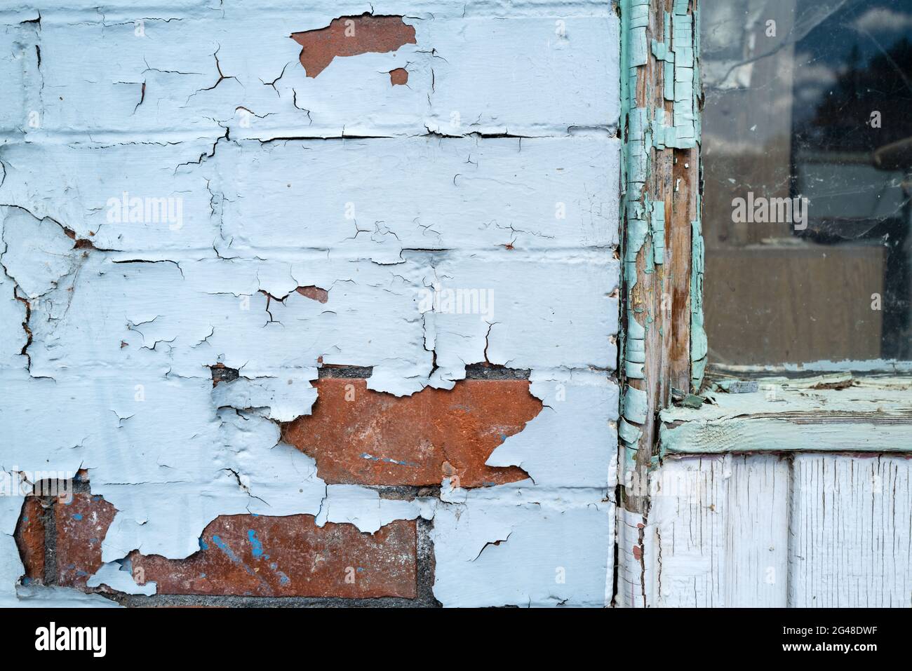 Blue paint is peeling from the brick facade of an abandoned building ...