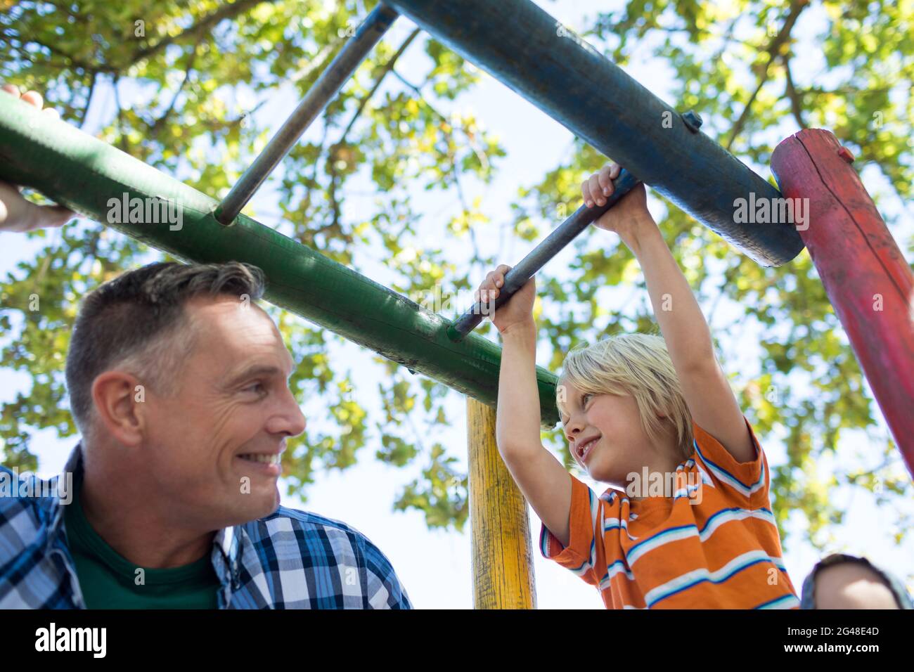 Low angle view of father and son playing on jungle gym Stock Photo - Alamy