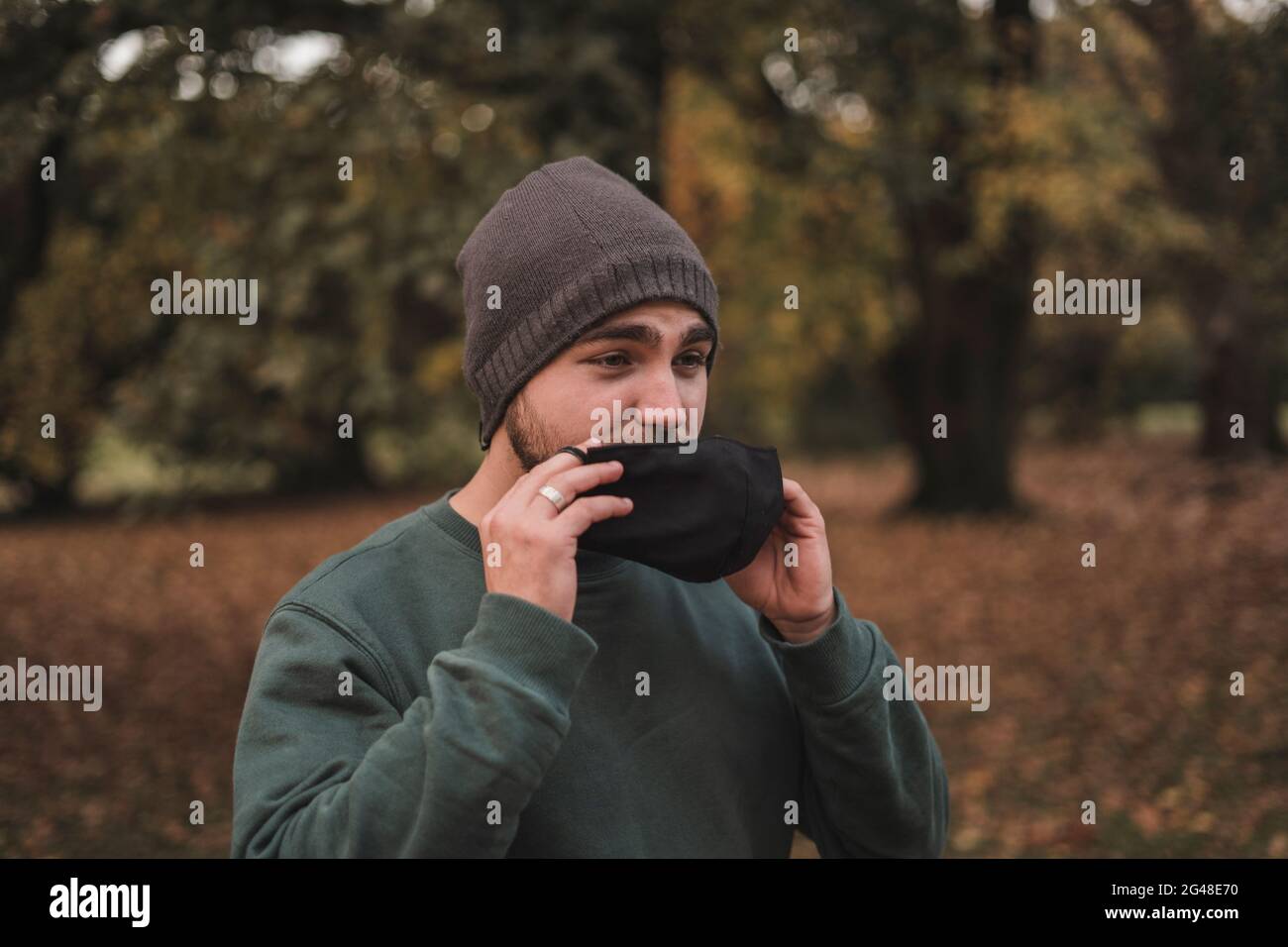 Young man taking off his mask in a park Stock Photo - Alamy