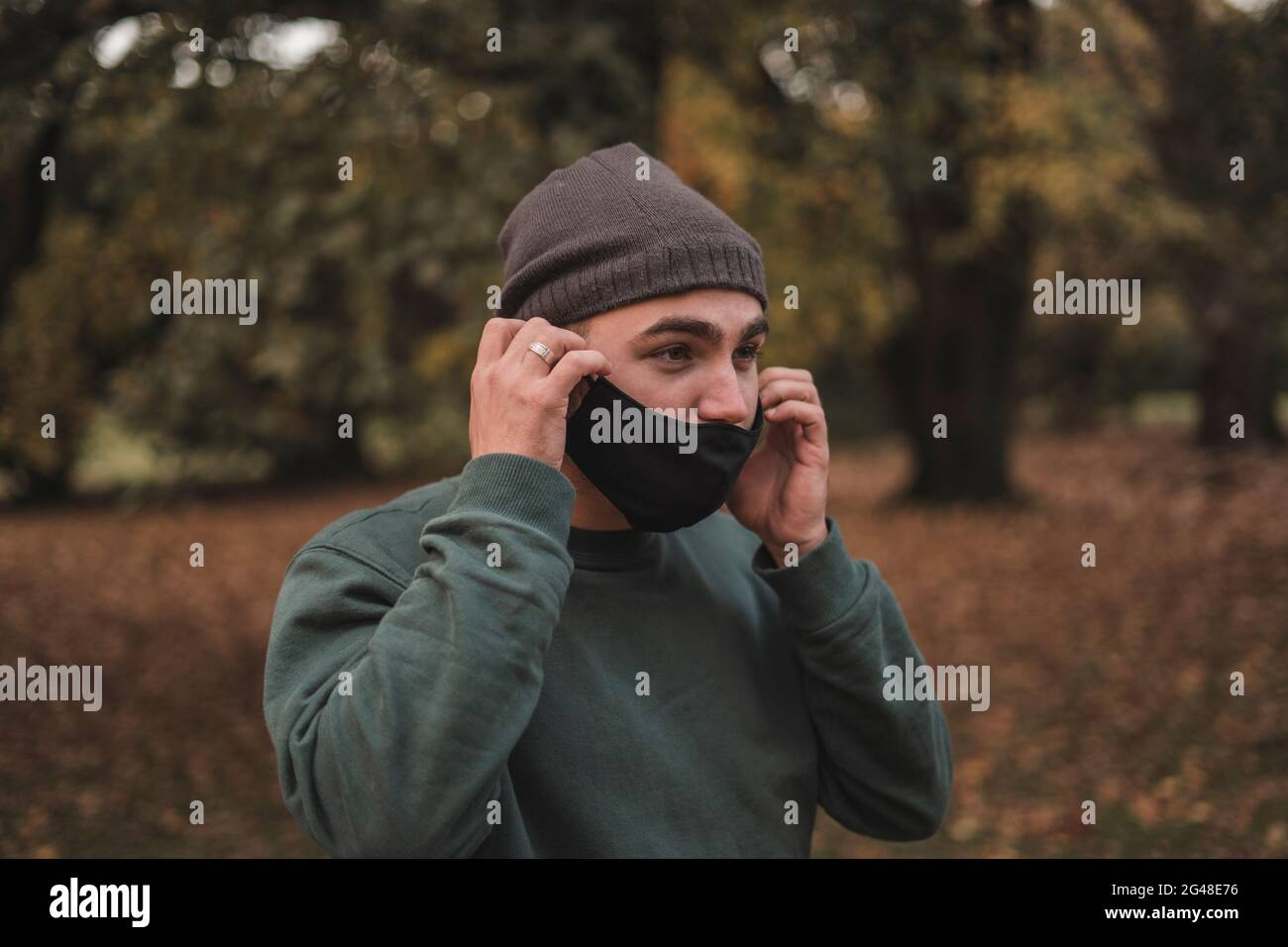 Young man taking off his mask in a park Stock Photo - Alamy