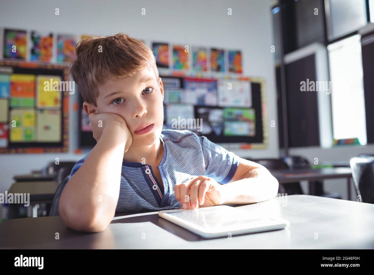 Boy leaning on desk while studying in classroom Stock Photo - Alamy