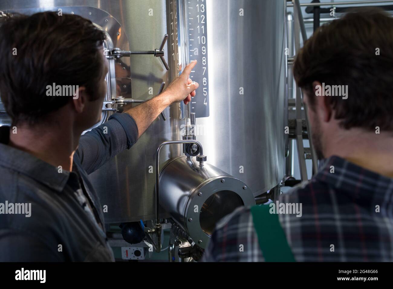 Worker explaining to coworker at brewery Stock Photo - Alamy