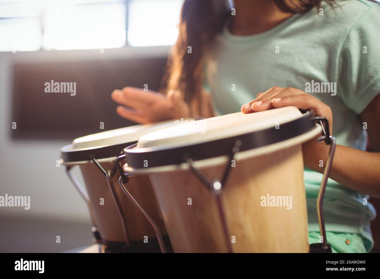 Mid section of girl playing bongo drums in classroom Stock Photo - Alamy