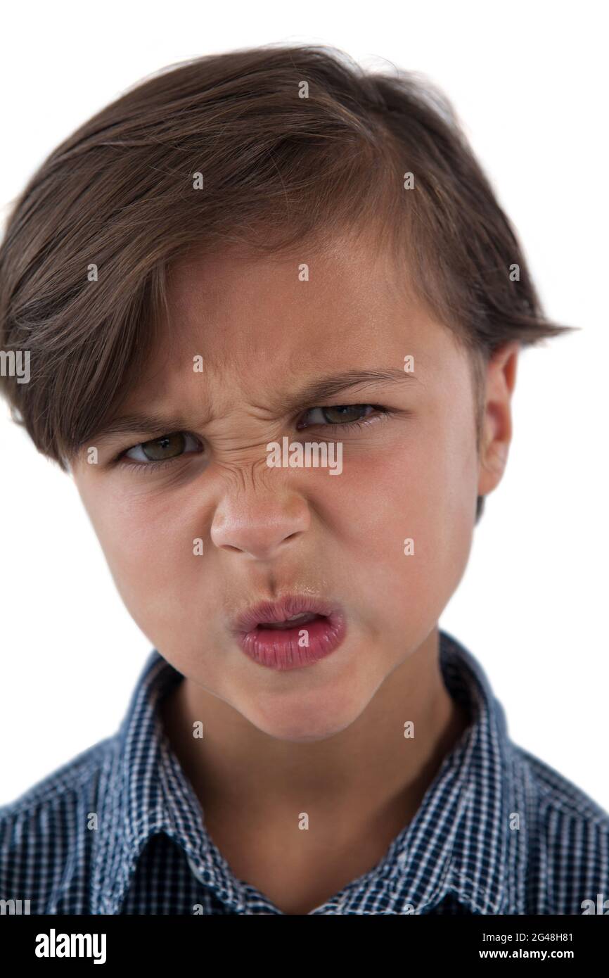 Annoyed boy standing against white background Stock Photo - Alamy
