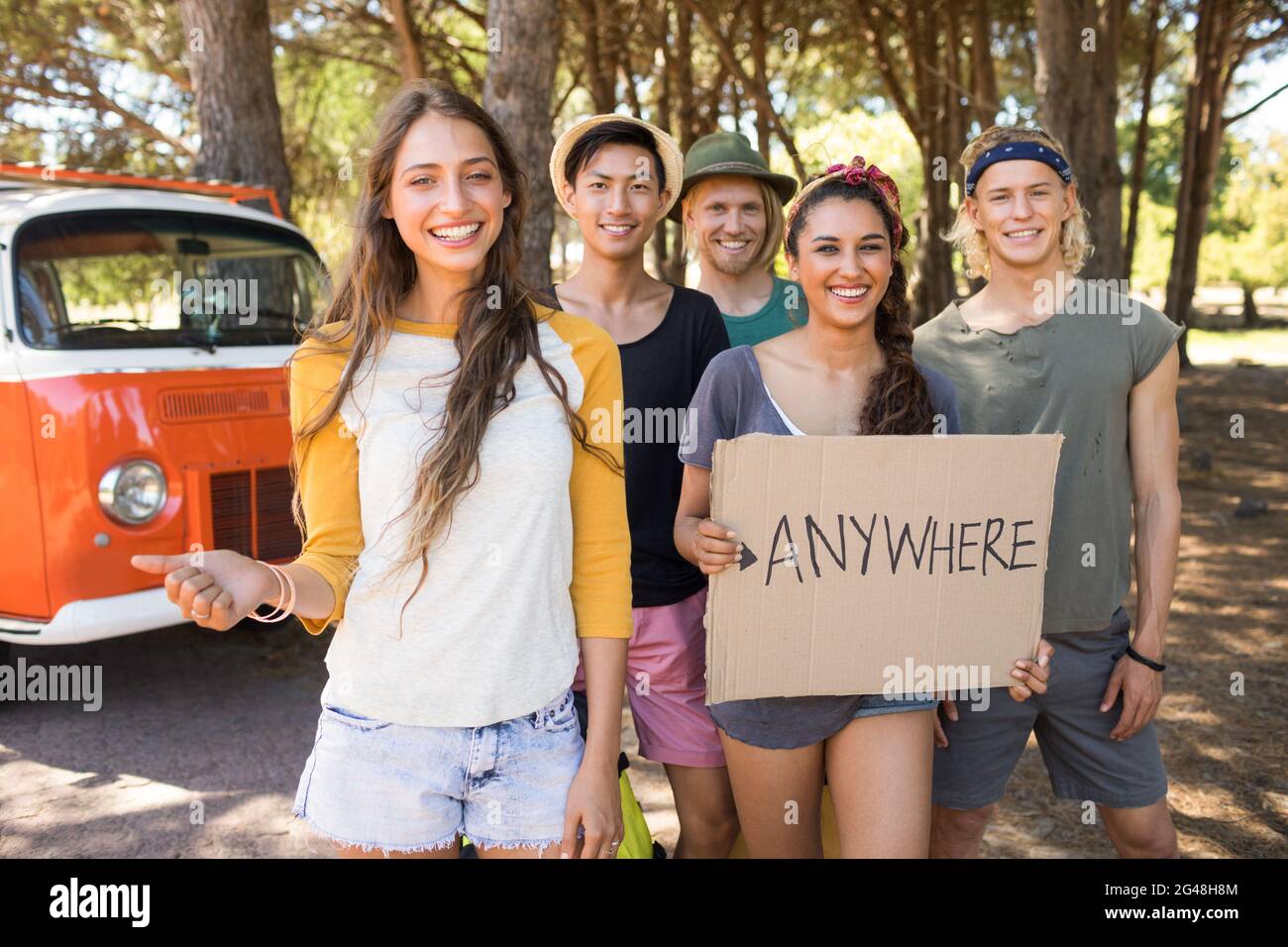 Portrait of cheerful friends with sign board Stock Photo - Alamy