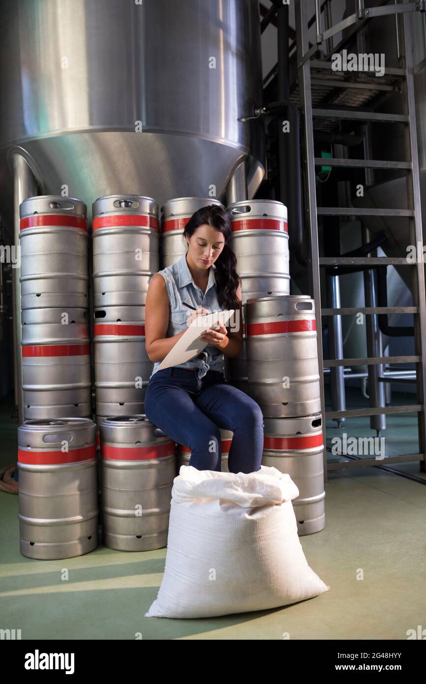Female worker writing on clipboard in factory Stock Photo - Alamy