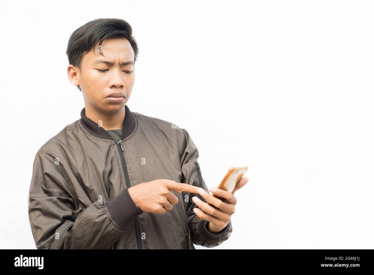 Indonesian guy with a jacket holding a phone and looking at it with a ...
