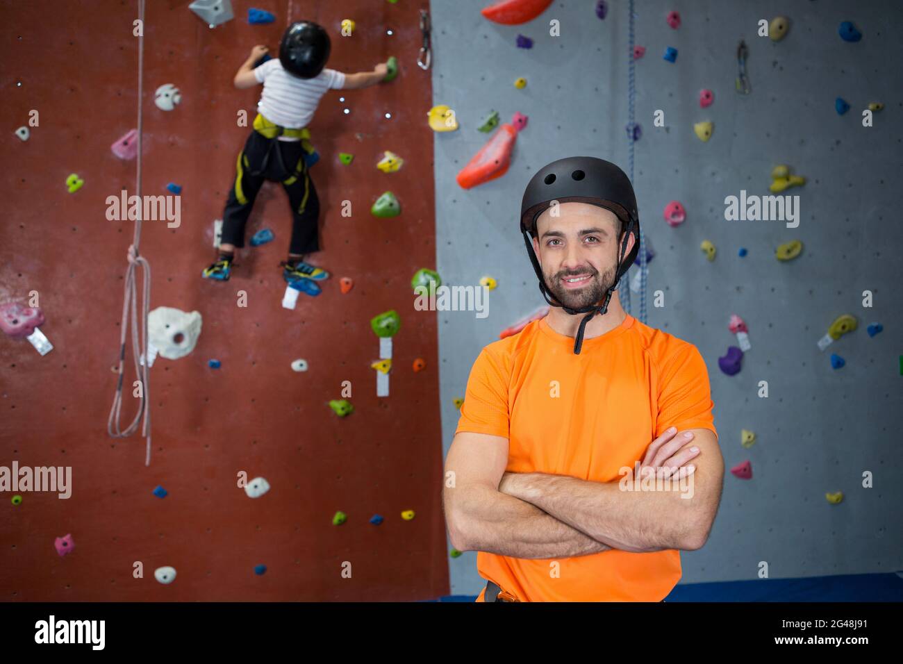 Trainer standing with arms crossed in fitness studio Stock Photo - Alamy