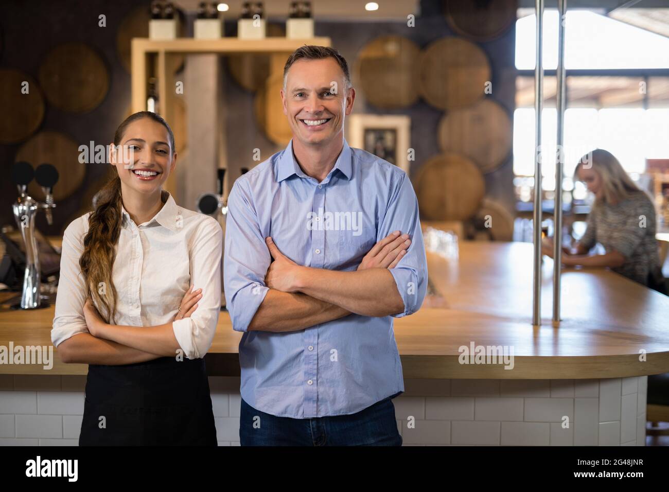 Couple standing with arms crossed near bar counter Stock Photo - Alamy