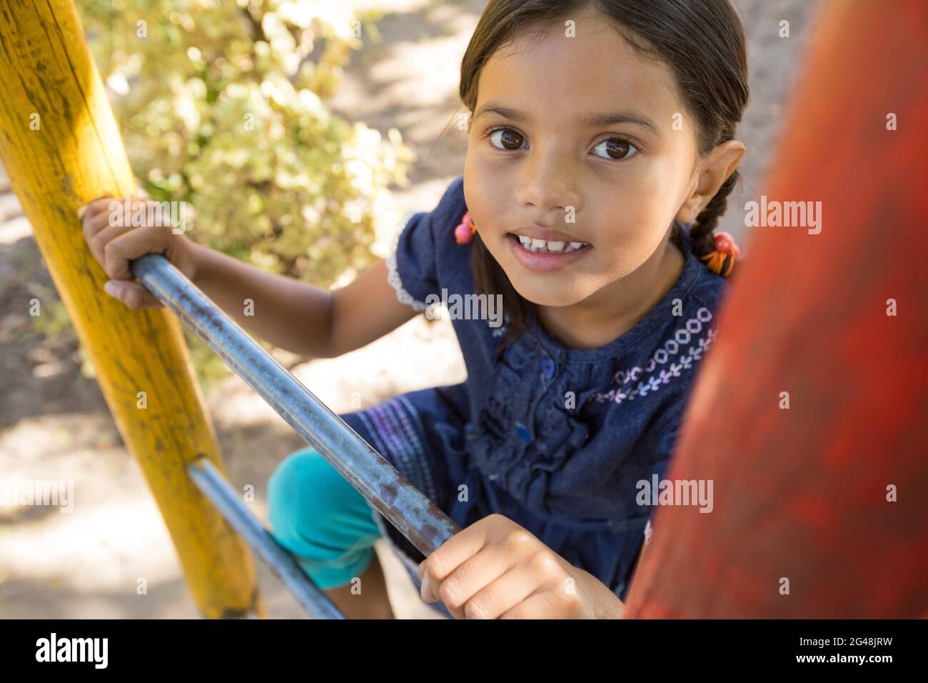 Portrait of girl climbing ladder of jungle gym Stock Photo - Alamy