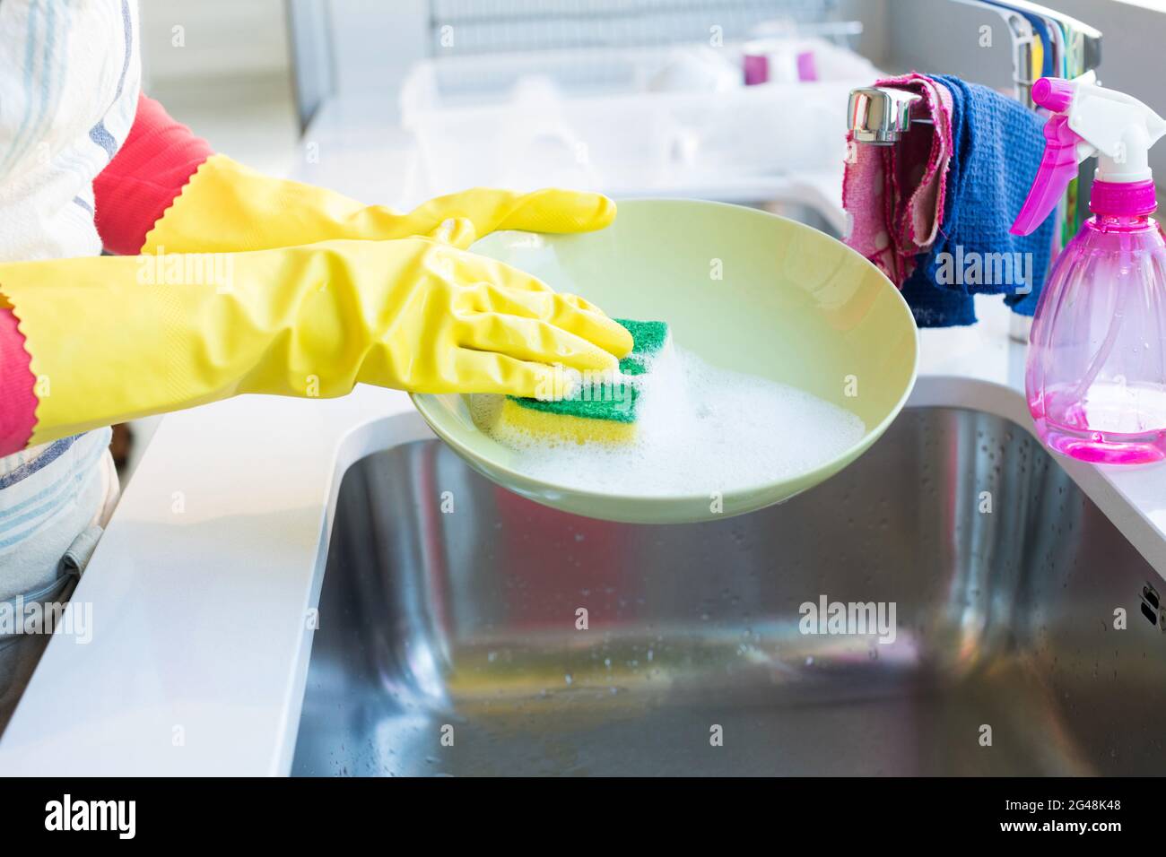 Woman washing plate with sponge in kitchen sink Stock Photo - Alamy