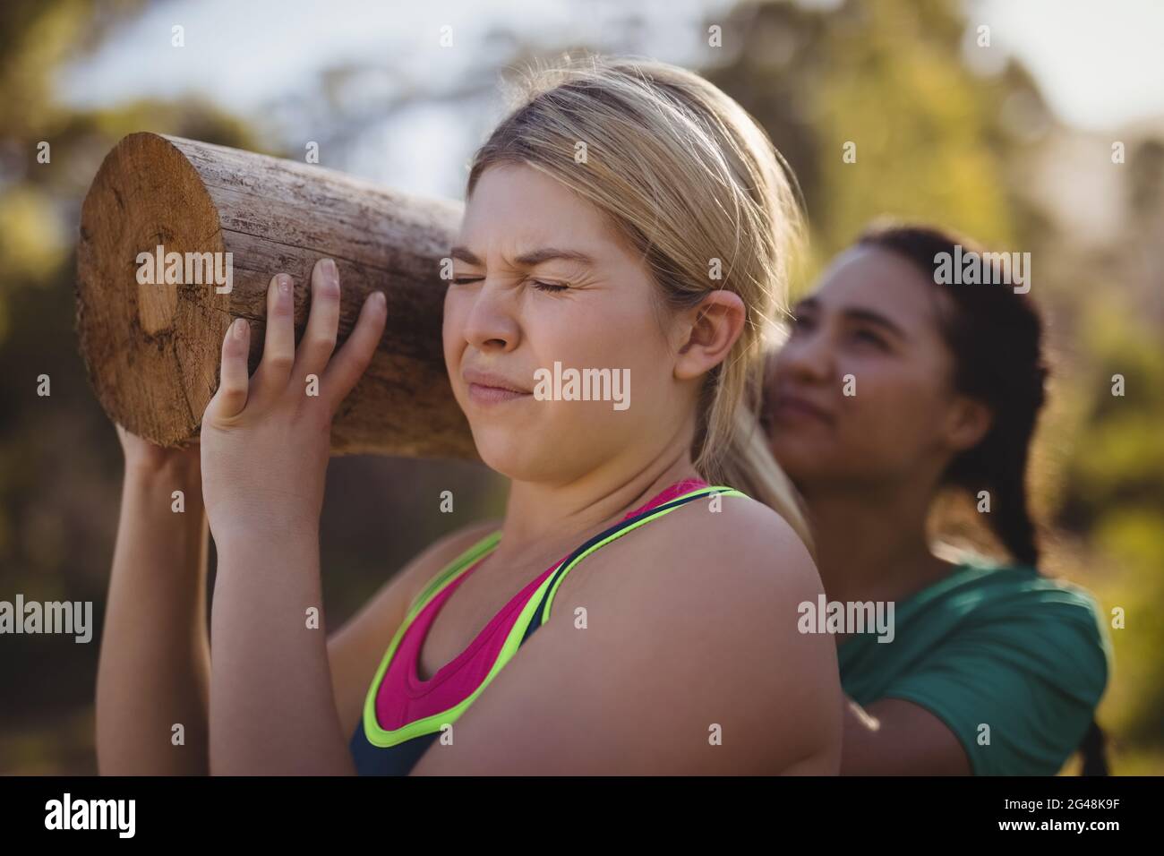 Trainer and woman carrying heavy wooden log Stock Photo - Alamy